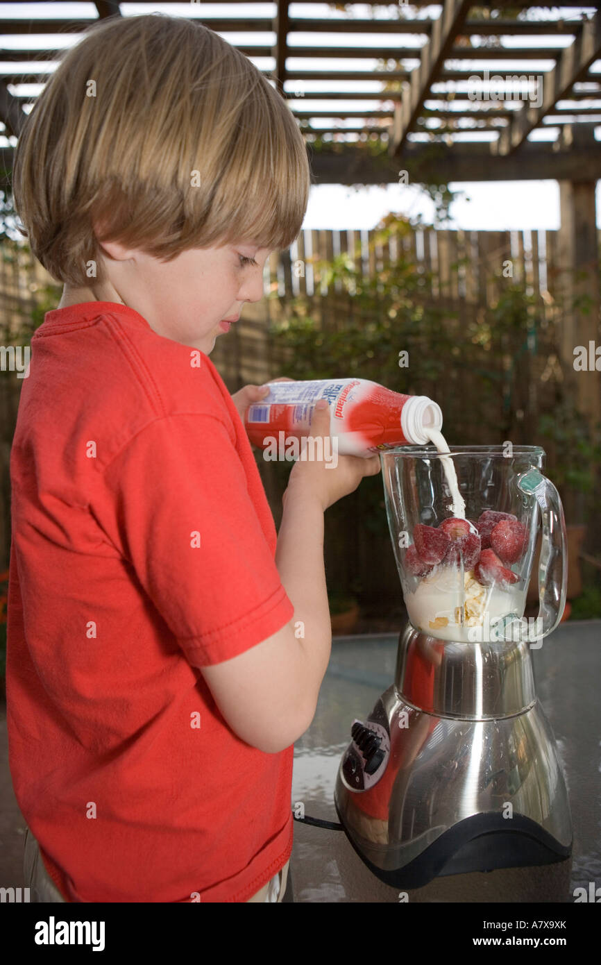 eight year old boy making home-made smoothie milkshake with fresh ...