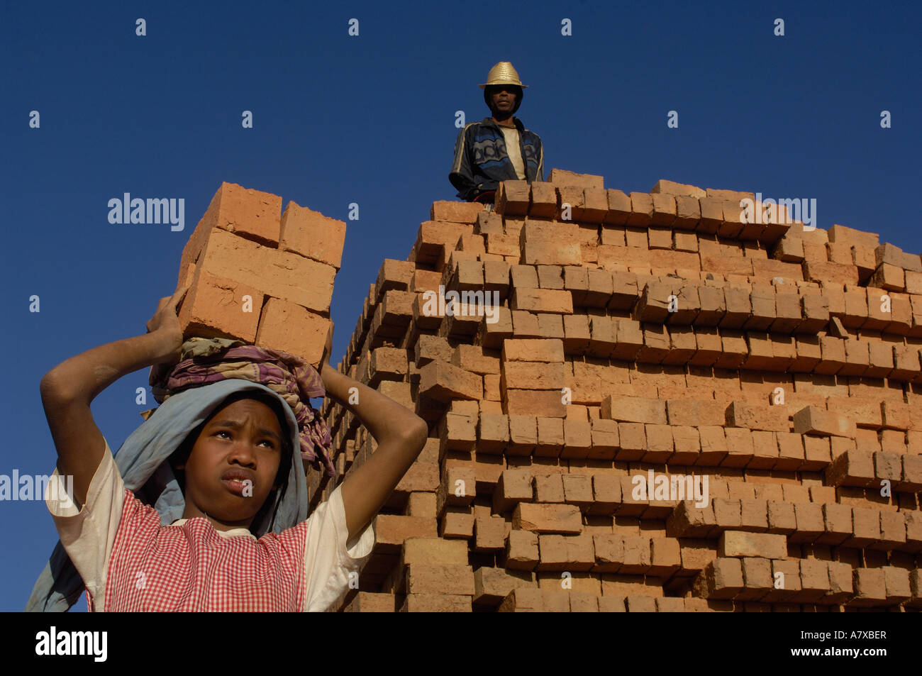 Child carrying bricks. In areas of Madagascar where the soil is ...