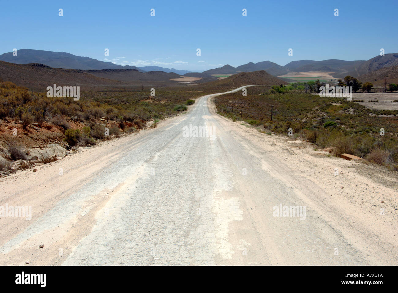 A gravel road leading through the Groot Swartberge mountain range in ...