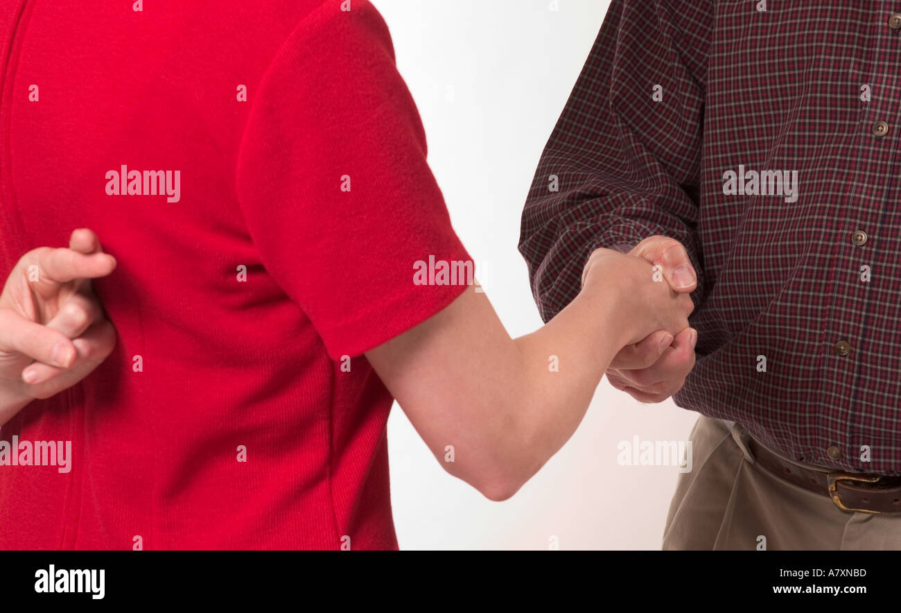 Woman shakes hands with man while fingers crossed behind back USA Stock ...