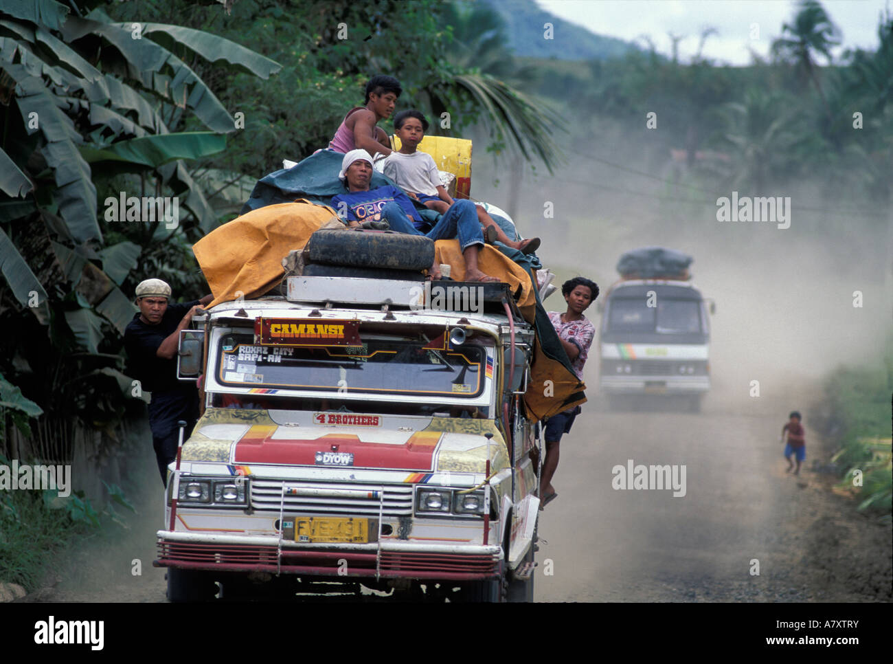 Philippines, Overloaded jeepney truck with passengers on roof drives ...