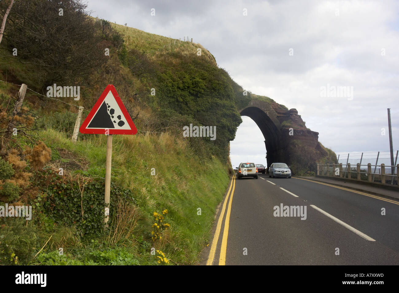 cars passing under red arch at falling rocks roadsign waterfoot ...
