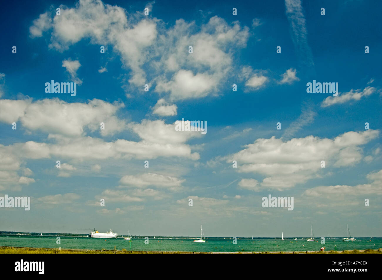 Cargo ship and private boats travelling in crowded Solent waters narrow ...
