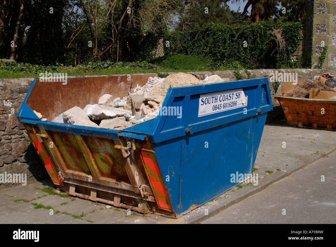 Skip filled with rubble outside in English street Stock Photo - Alamy