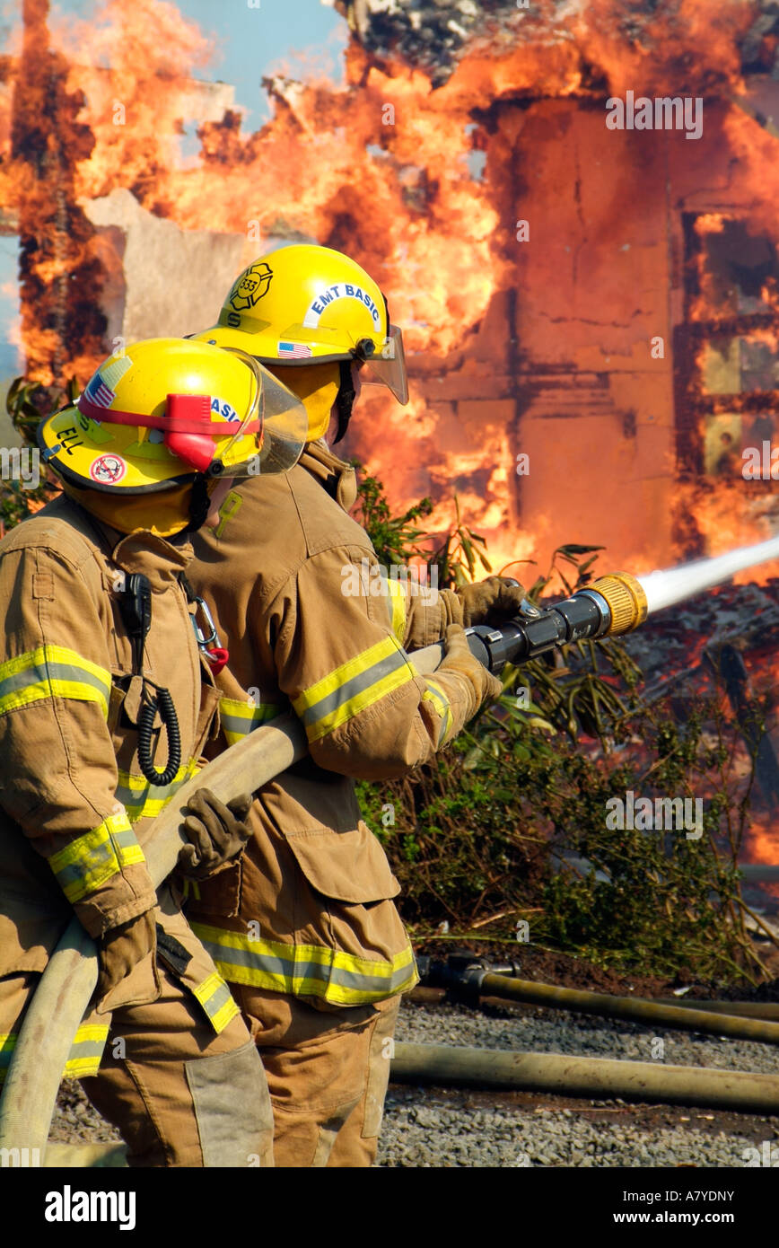 Two firefighters use a powerful hose to blast water onto the billowing ...