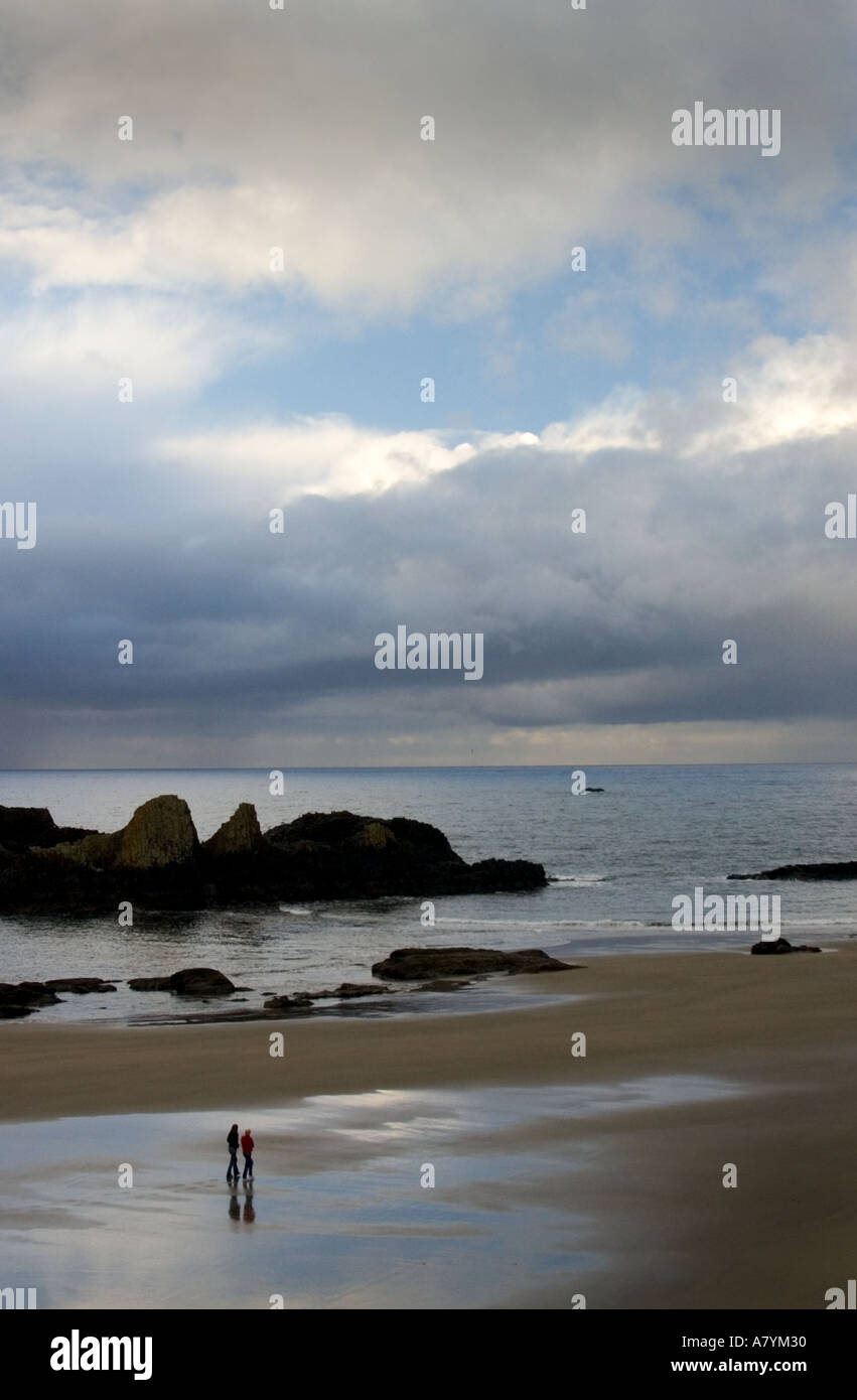 Two people walk on the beach during low tide in Seal Rock Oregon Stock ...