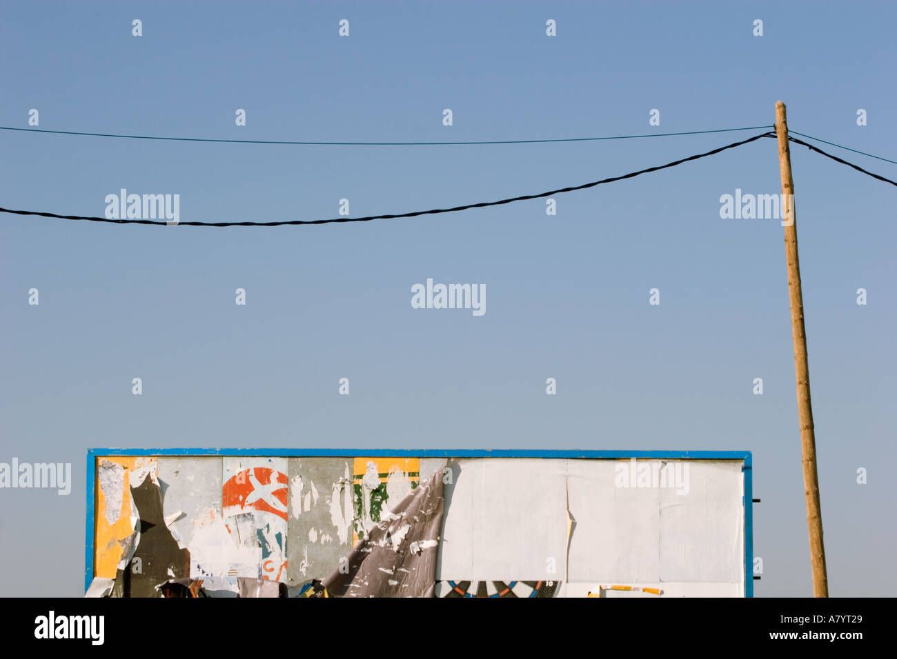 Old unused advertising hoarding board and cheap pole with telephone and ...