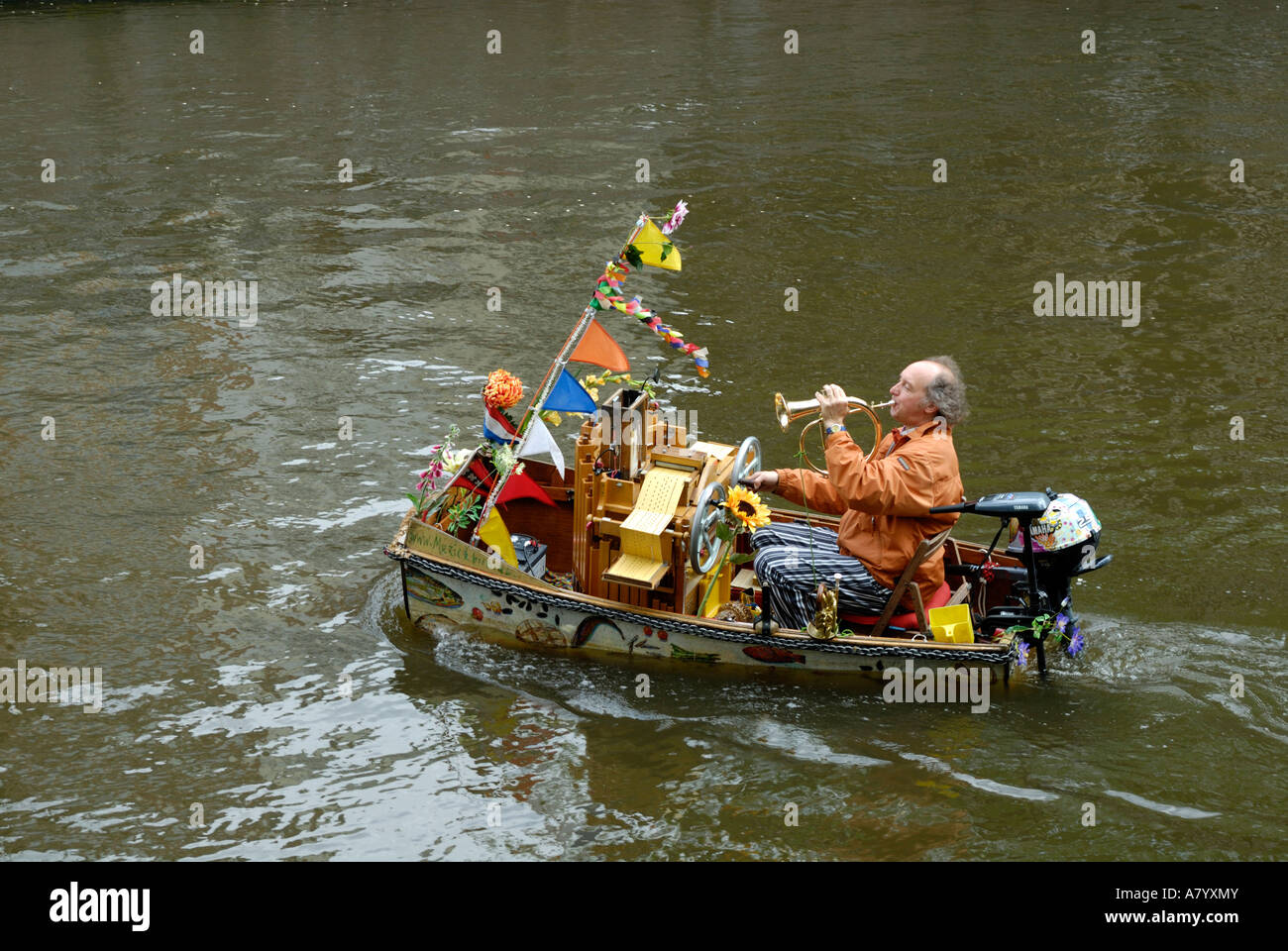 A busker playing trumpet in a small boat on a canal in Amsterdam Stock ...