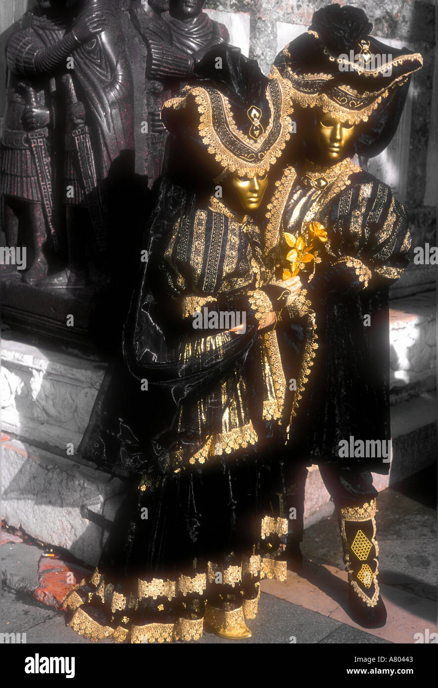Two masked carnival figures dressed in black and gold costumes Venice ...