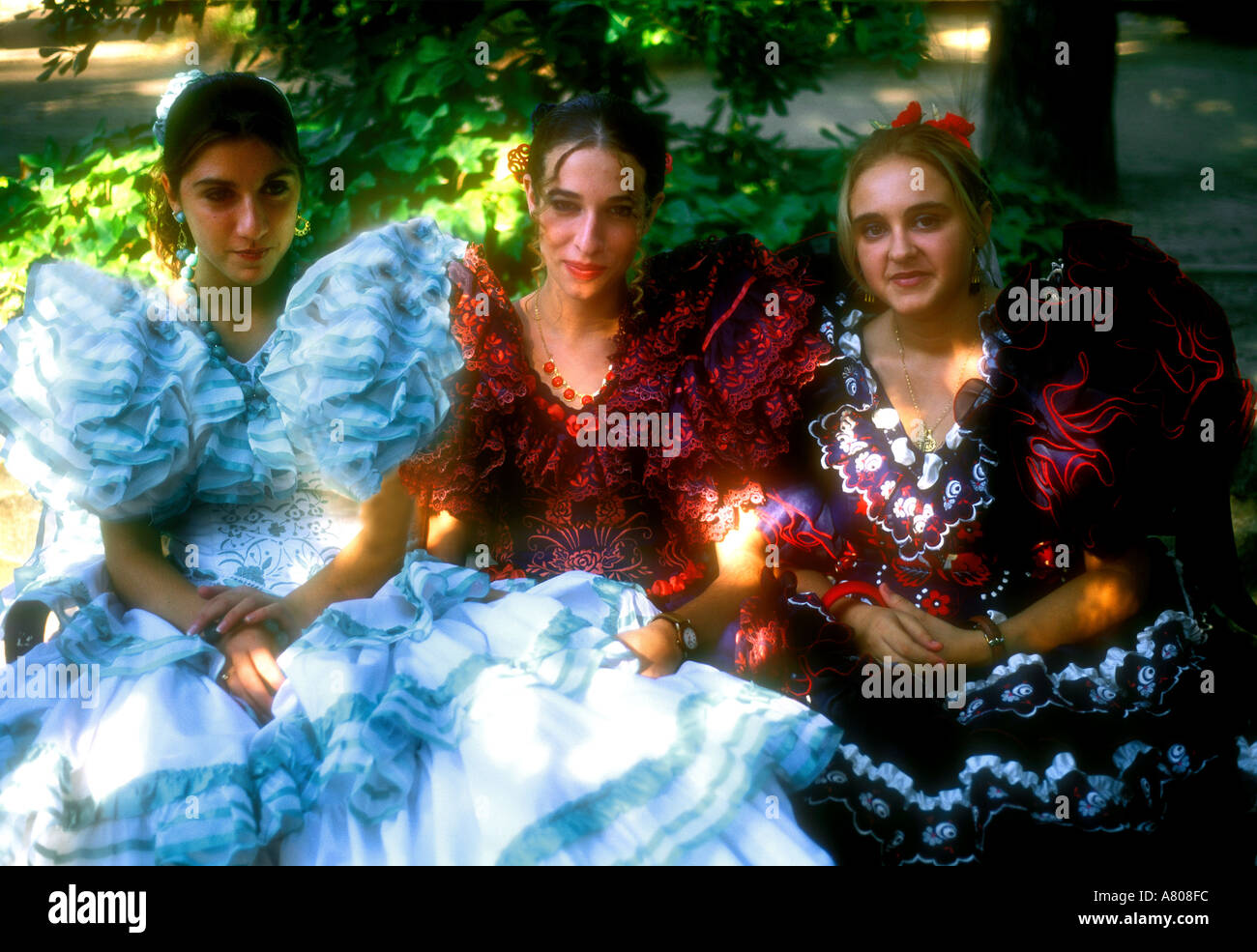 Three young Spanish women dressed for fiesta in traditional flamenco ...
