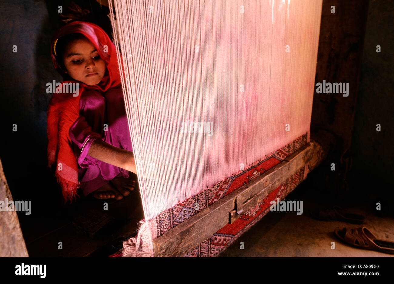 Pakistan, Lahore, child with work on a weaving loom in a village in the ...