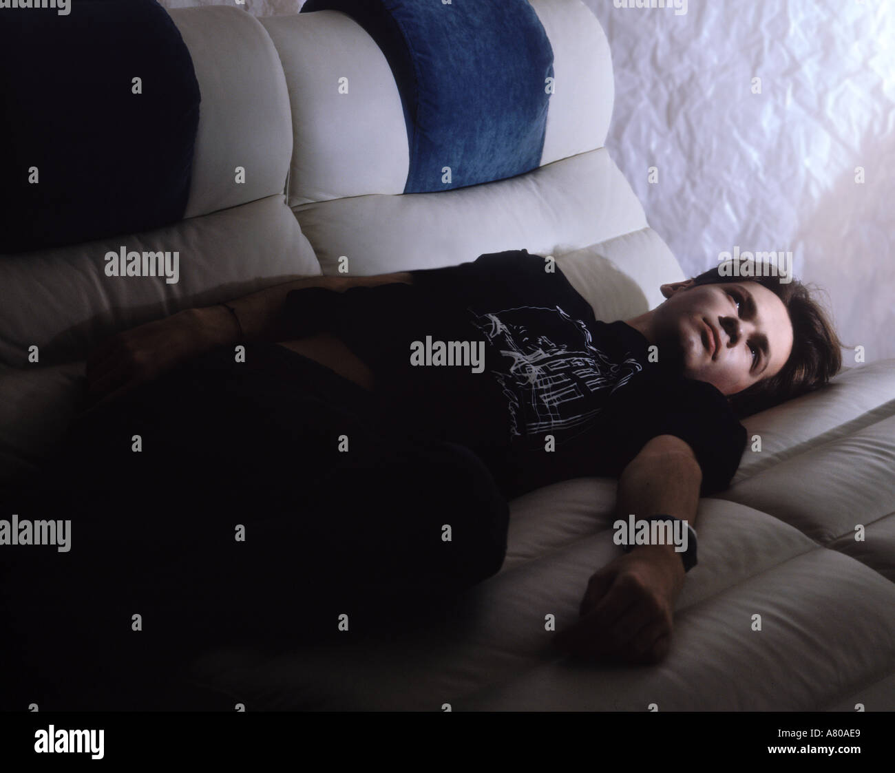 Young man lying on the sofa Stock Photo - Alamy