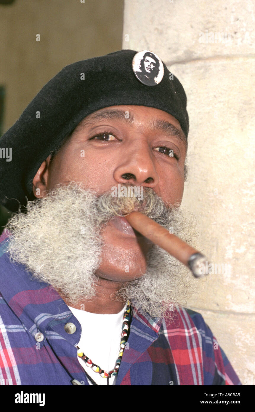 Cuban man with unusual beard in colourful dress smokes cigar in old ...