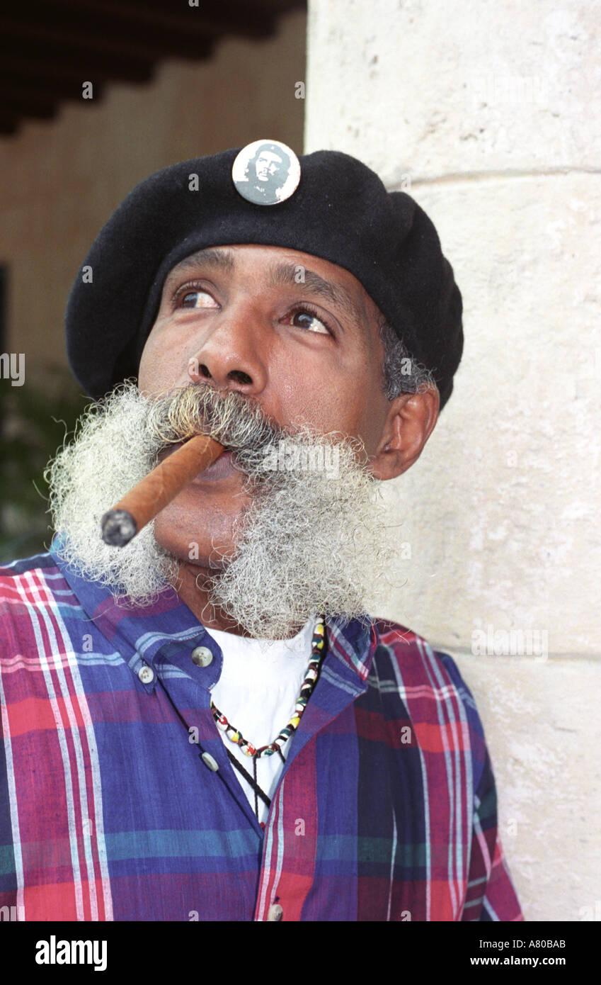 Cuban man with unusual beard in colourful dress smokes cigar in old ...