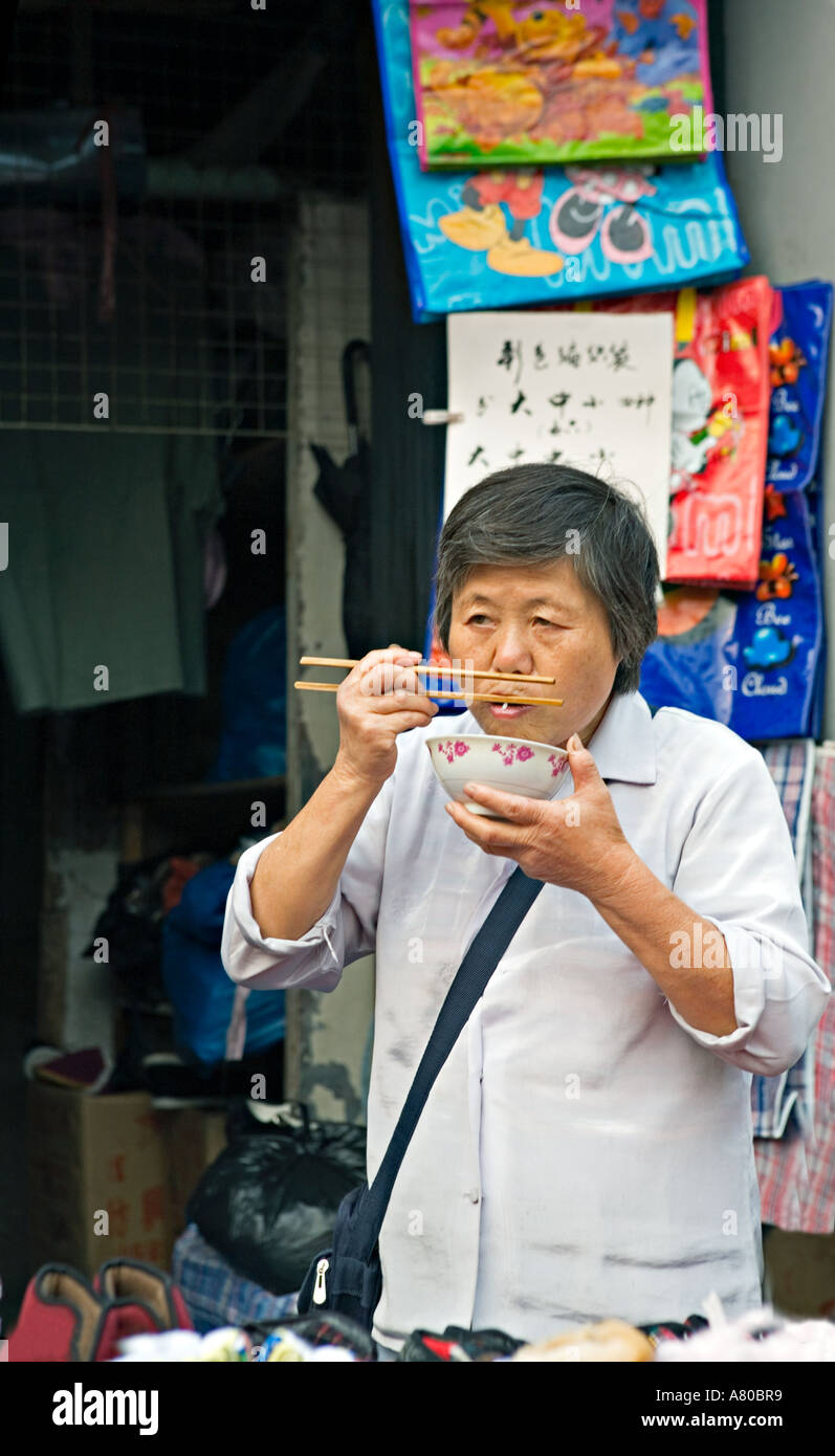 CHINA SHANGHAI Female Chinese merchant eating lunch of noodles with ...
