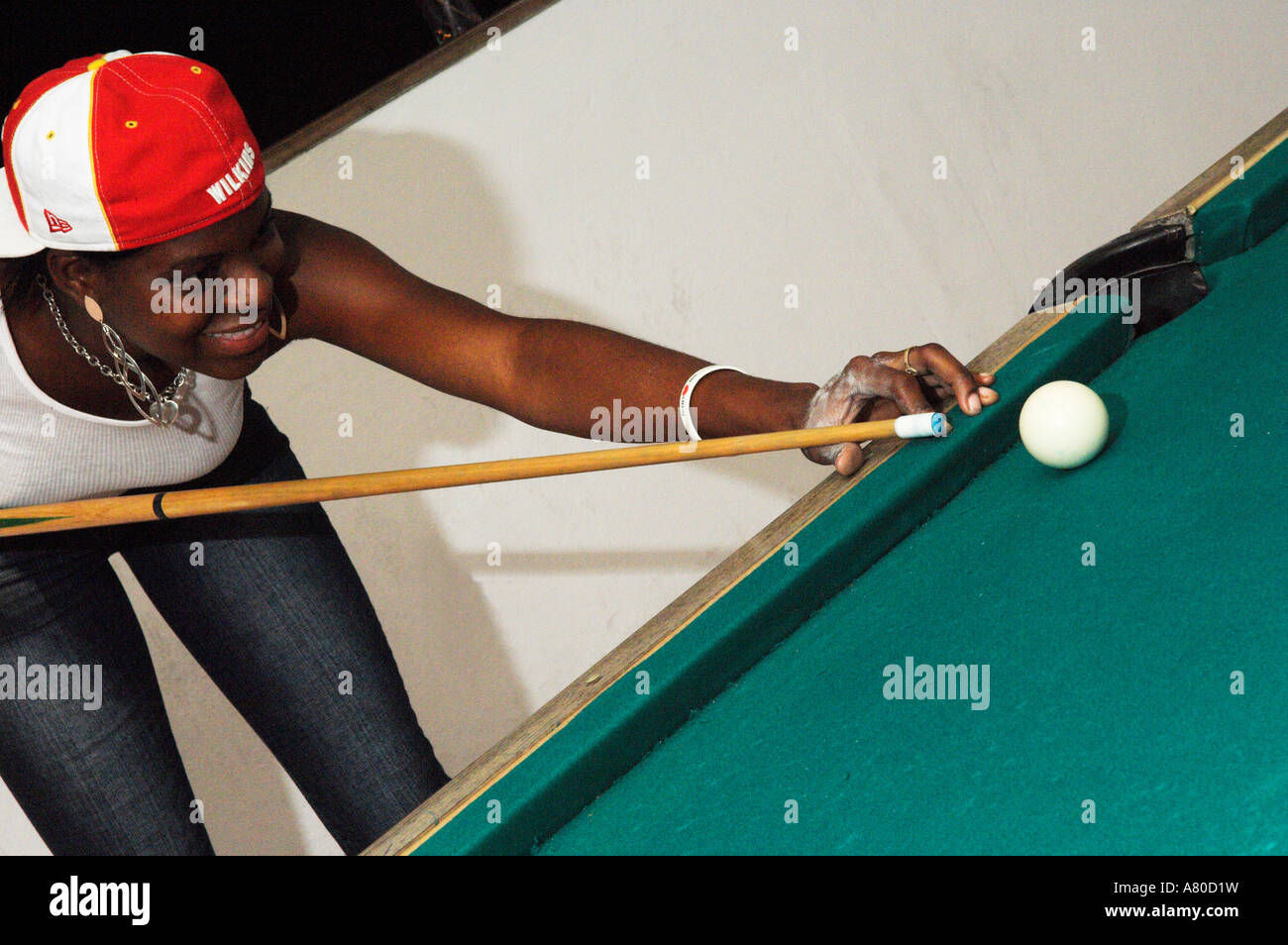 Black woman pool player with cue about to hit white ball on pool table ...