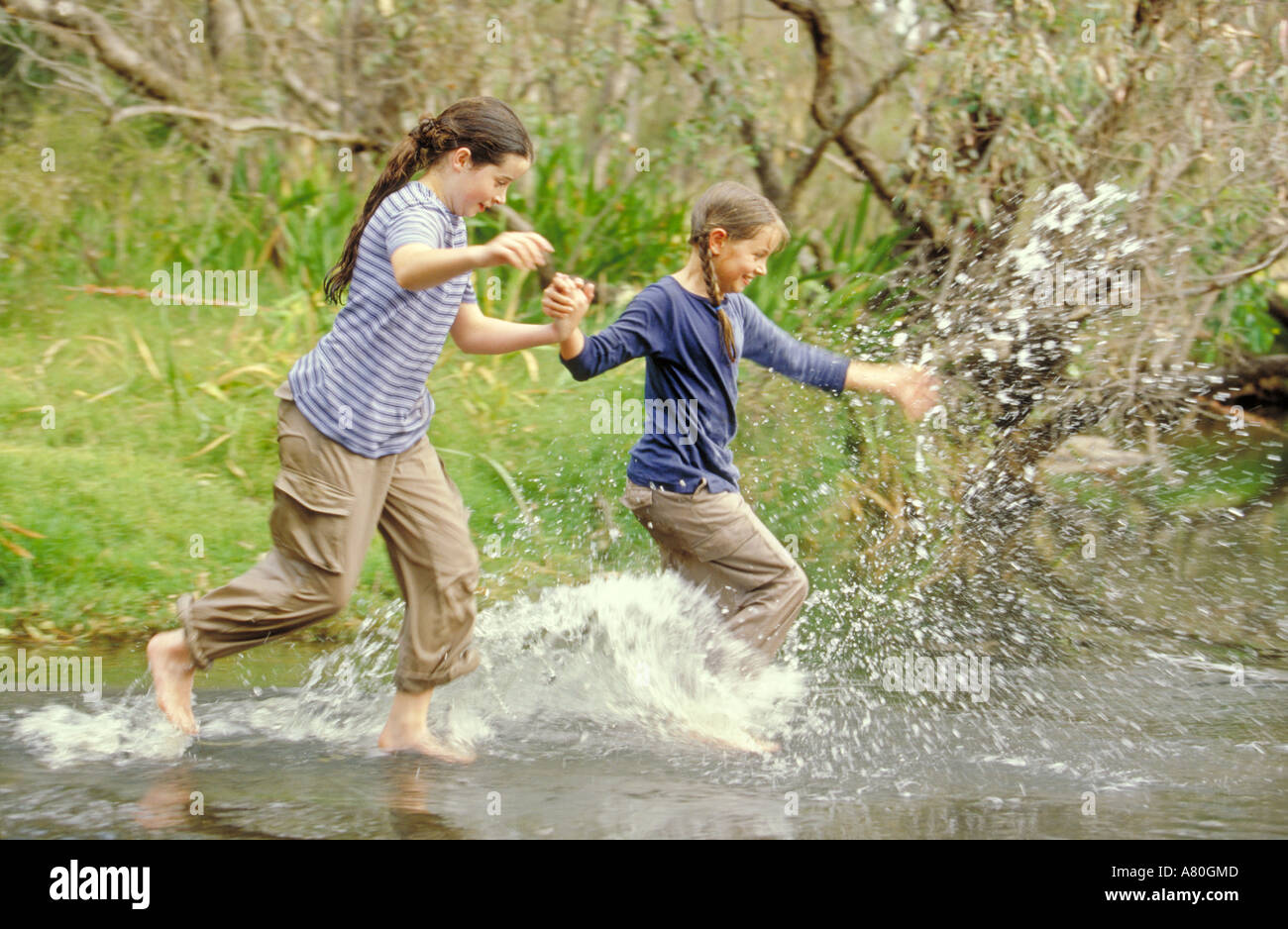 two female teenager running across through a river Stock Photo - Alamy