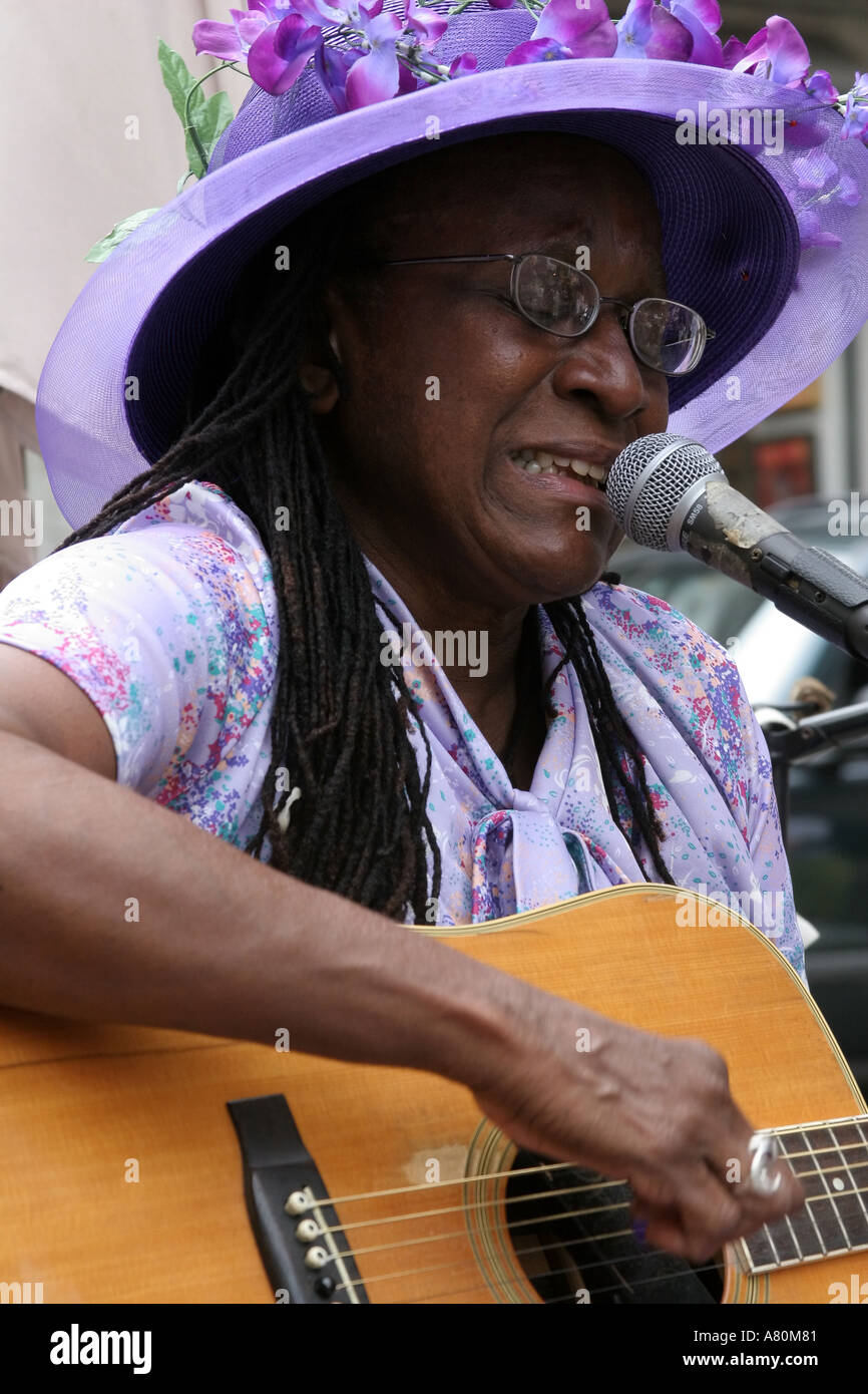 An elderly woman play the guitar and sings during a street performance ...