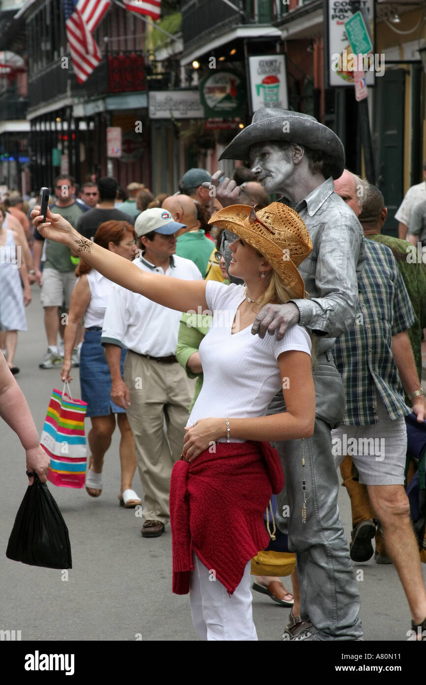 A silver cowboy statue street performer poses with a young blonde ...