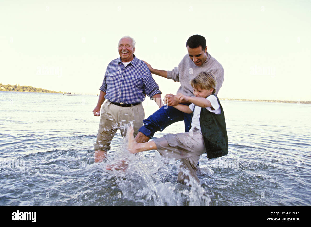 grandfather son and grandchild wading across a lake Stock Photo - Alamy
