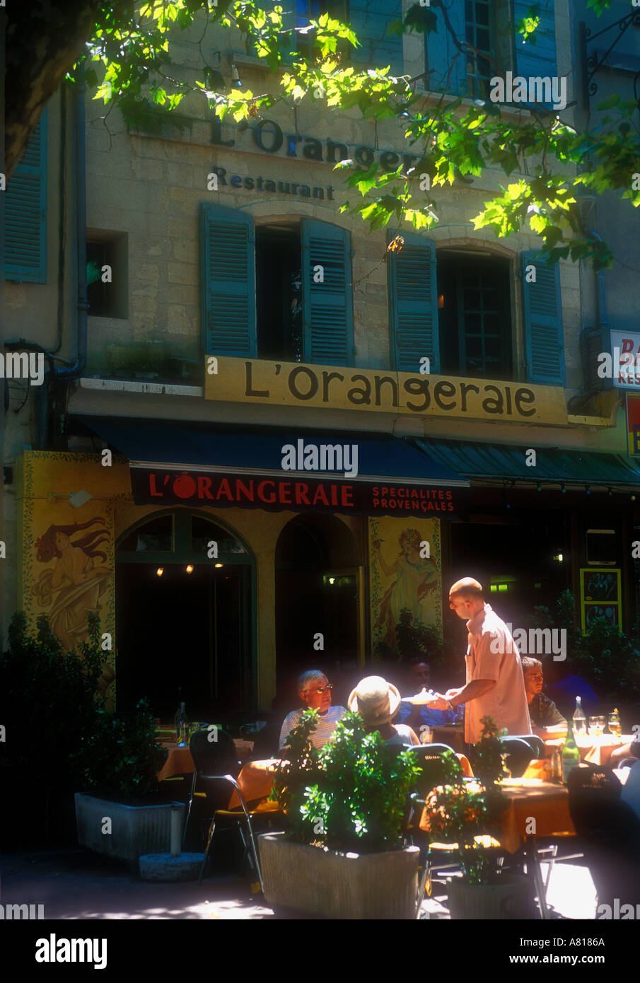 A waiter and customers dining outside at a restaurant in Avignon ...