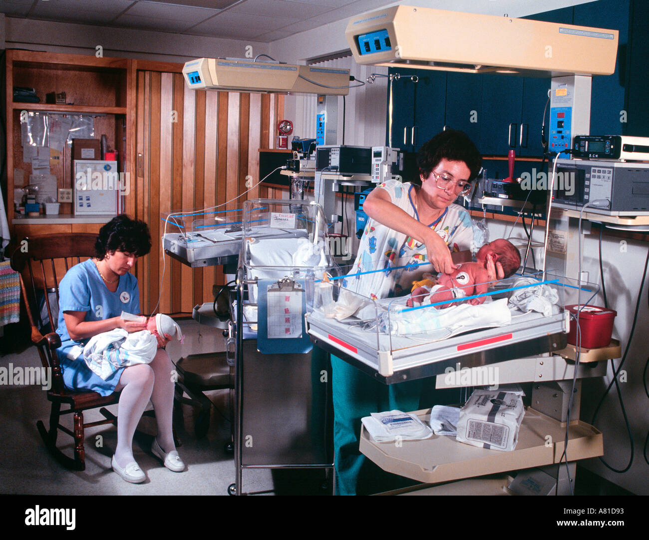 one nurse feeds and another puts monitoring devices on a baby in the ...
