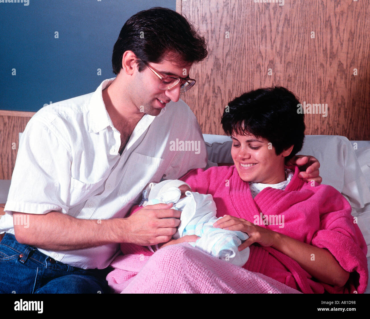 mother and father look at their new born baby in the birthing suite at ...
