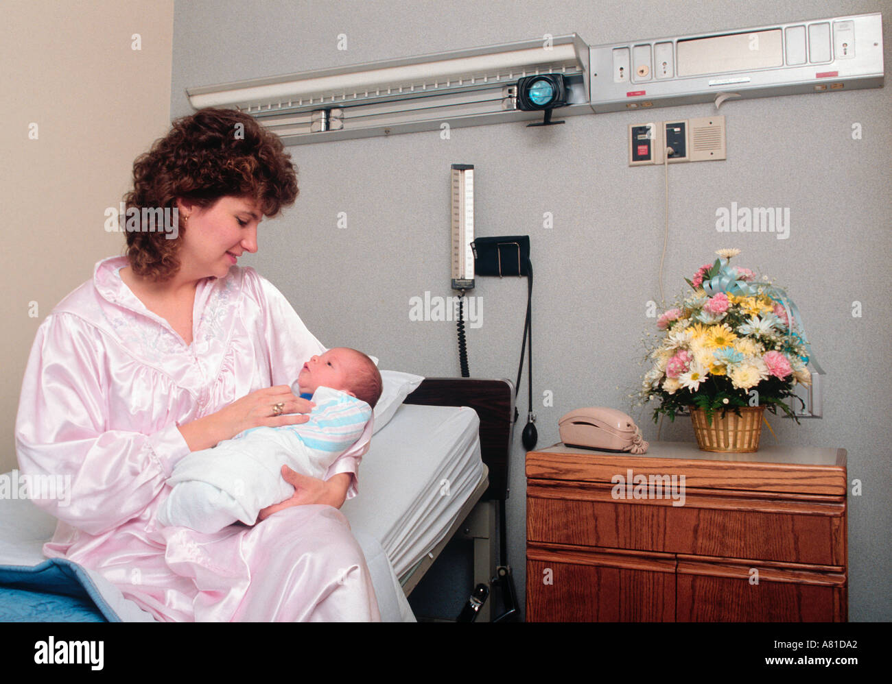 Mother looks at her new born baby in the hospital birthing suite room ...