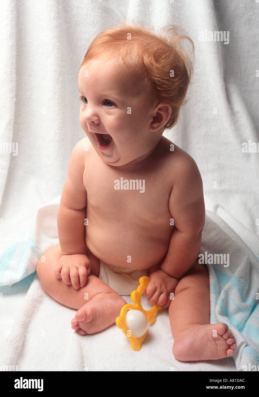 a baby smiles and plays with its rattle in diapers Stock Photo - Alamy