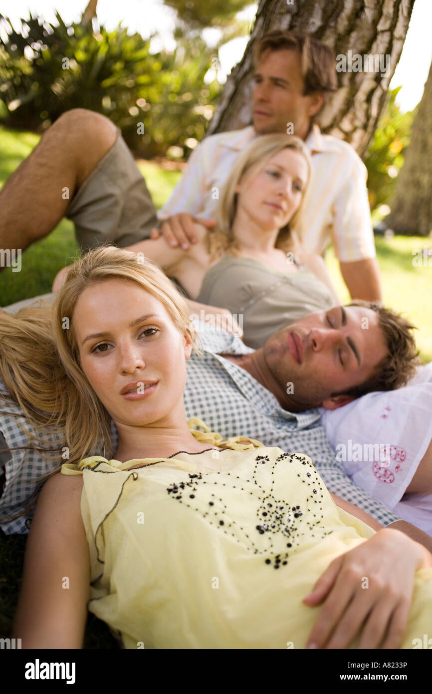 Two couples outdoors leaning on a tree trunk Stock Photo - Alamy