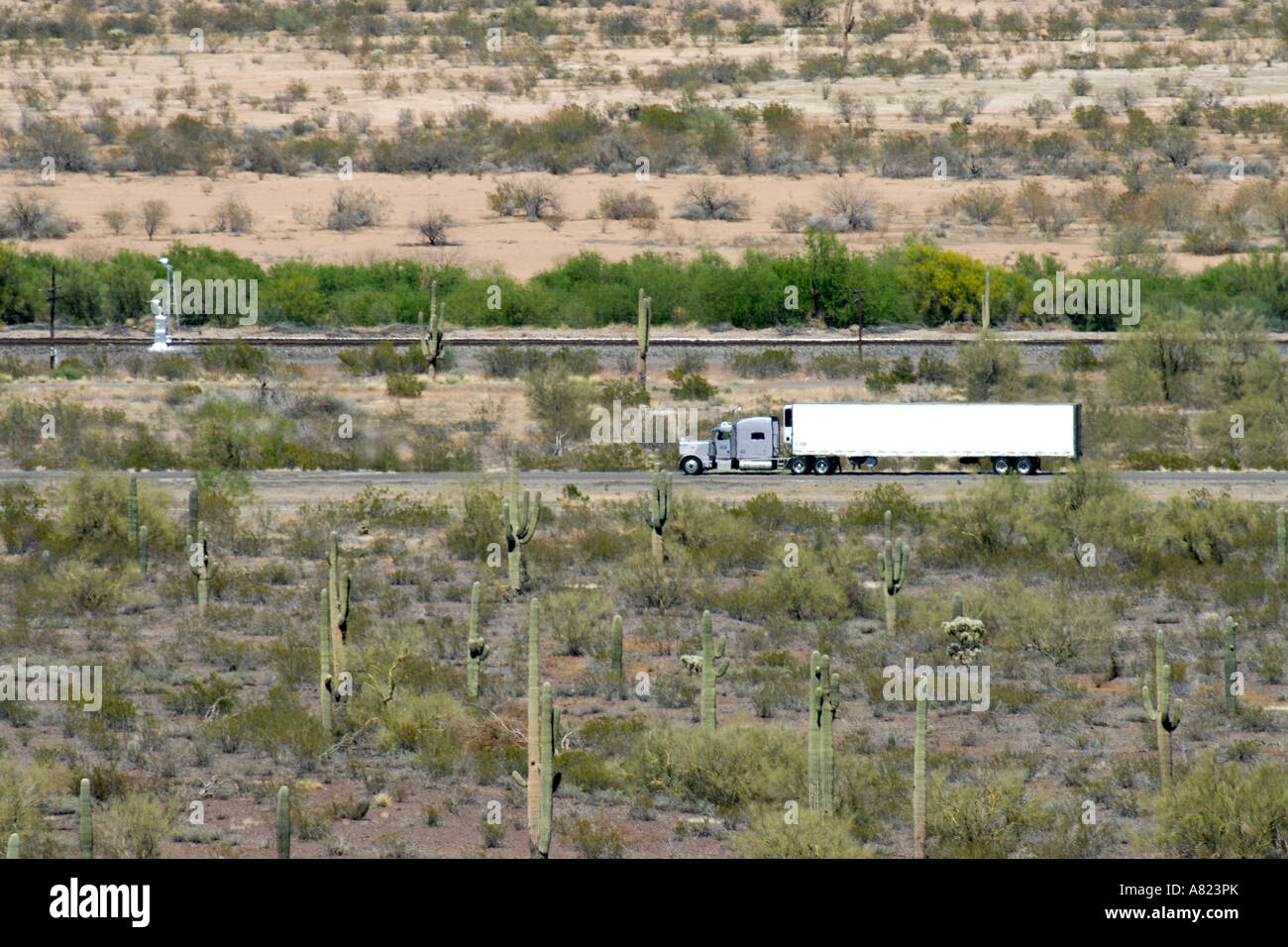 Semi truck traveling thru the desert with railroad tracks in background ...