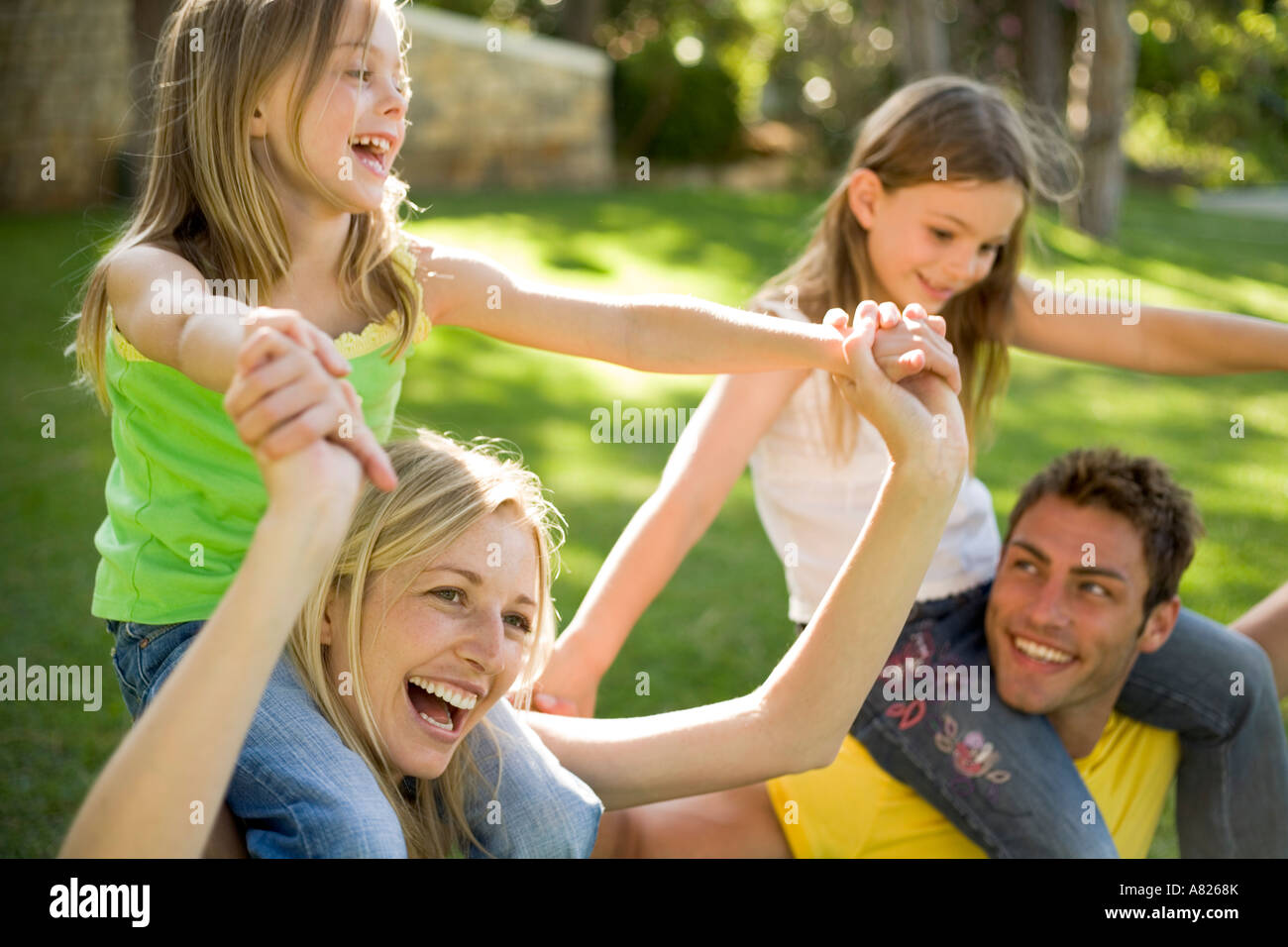 Parents giving their daughters shoulder rides at a park Stock Photo - Alamy