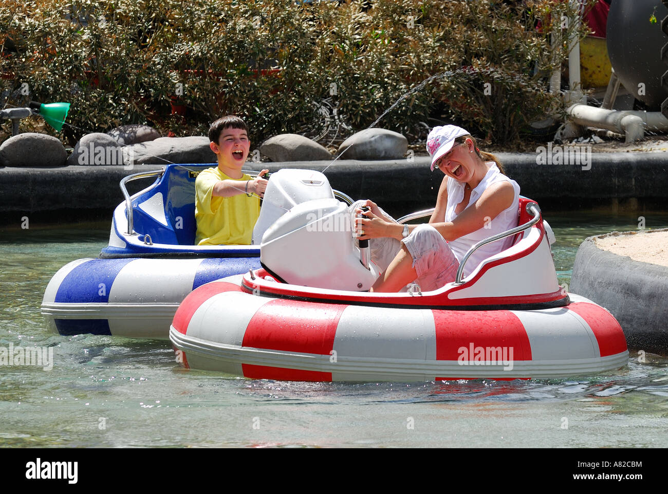 Young boy spraying mother with water at amusment park Stock Photo - Alamy