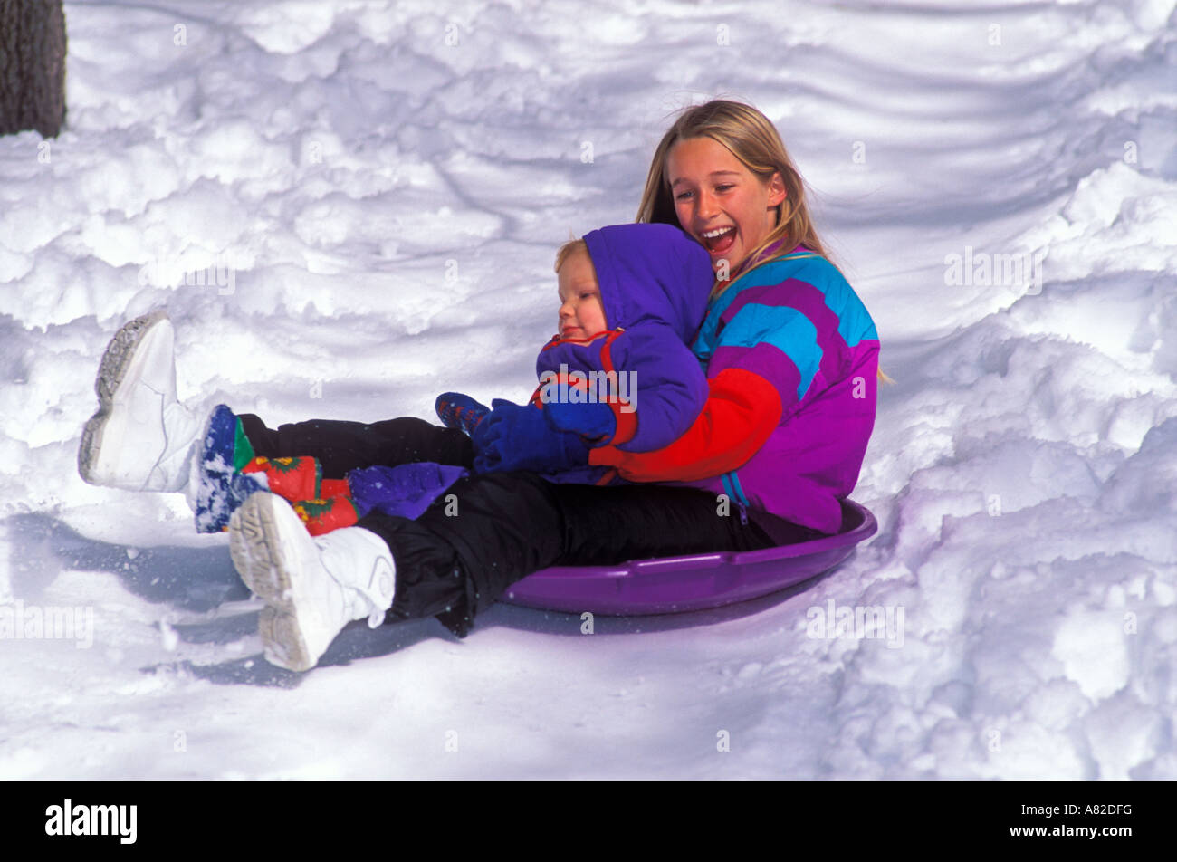 Kids ages 2 and 10 years riding a snow dish San Bernadino Mountains ...
