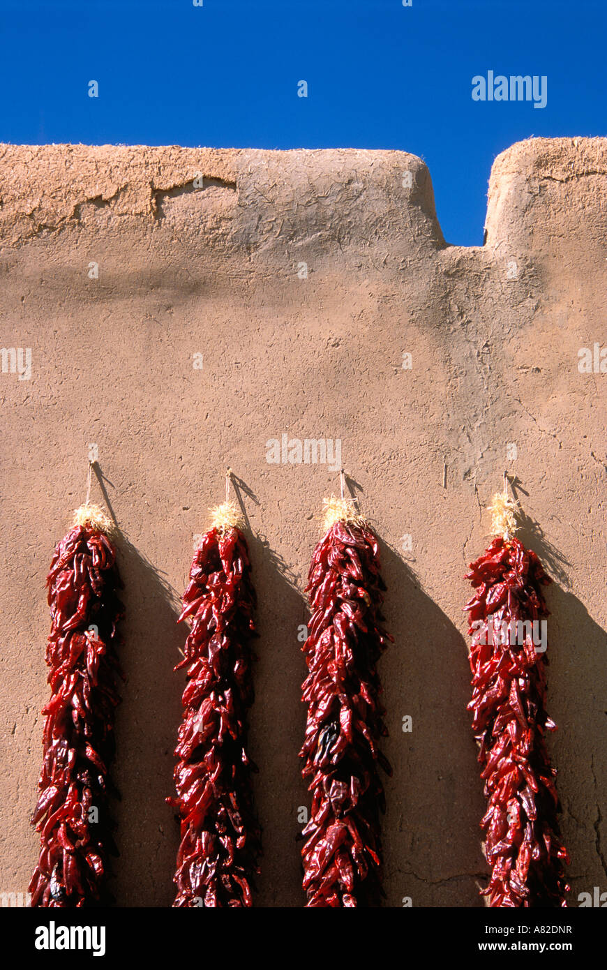 Large chili ristras on adobe wall at the entrance to the Martinez ...