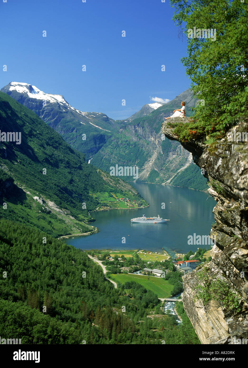 Woman sitting at Flydalsjuvet above Geiranger Fjord or Geirangerfjord ...