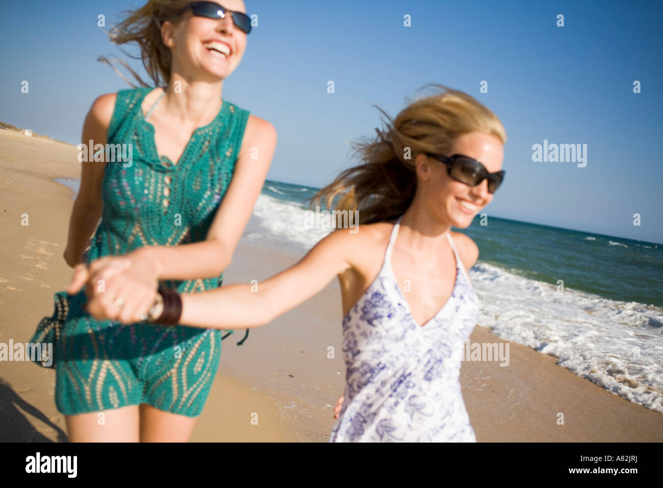 Two women skipping down the beach Stock Photo - Alamy