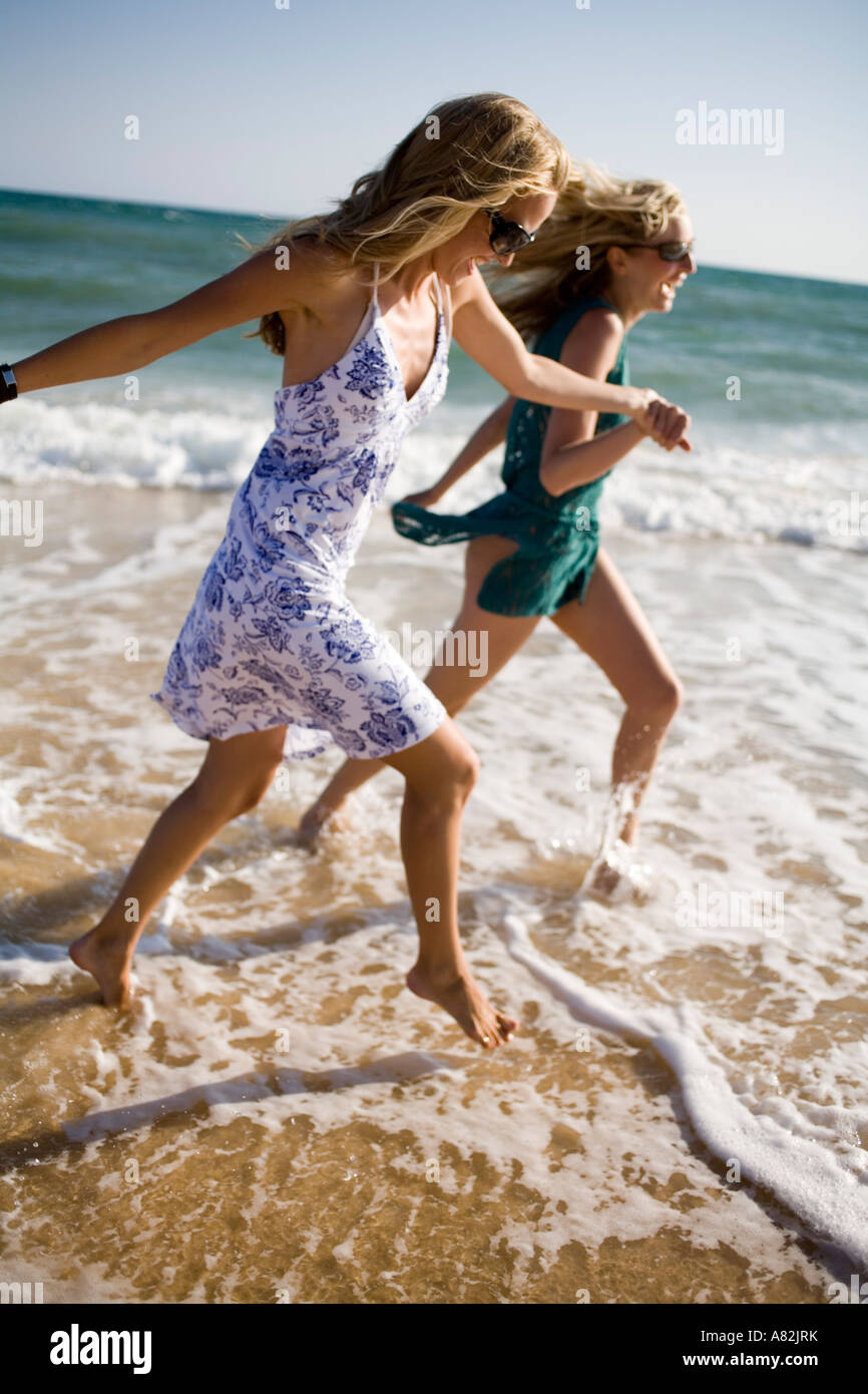 Two women skipping down the beach Stock Photo - Alamy