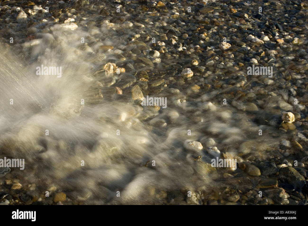 Water flowing over pebbles on a beach Stock Photo - Alamy