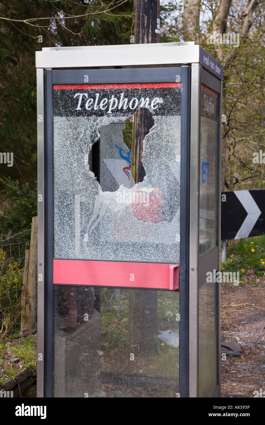 Vandalised modern rural telephone box with hole through broken glass ...