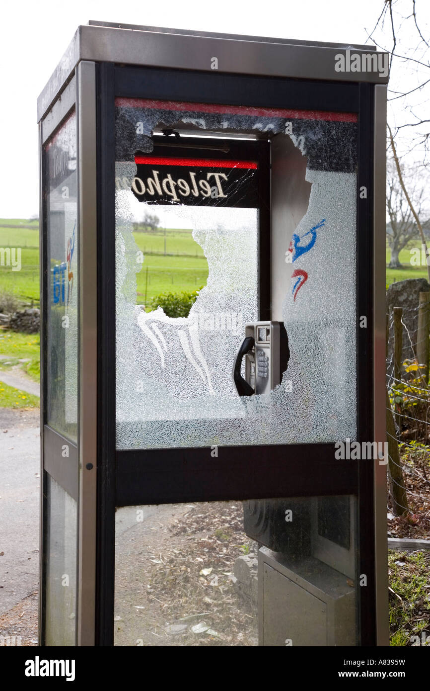 Vandalised modern rural telephone box with hole through broken glass ...