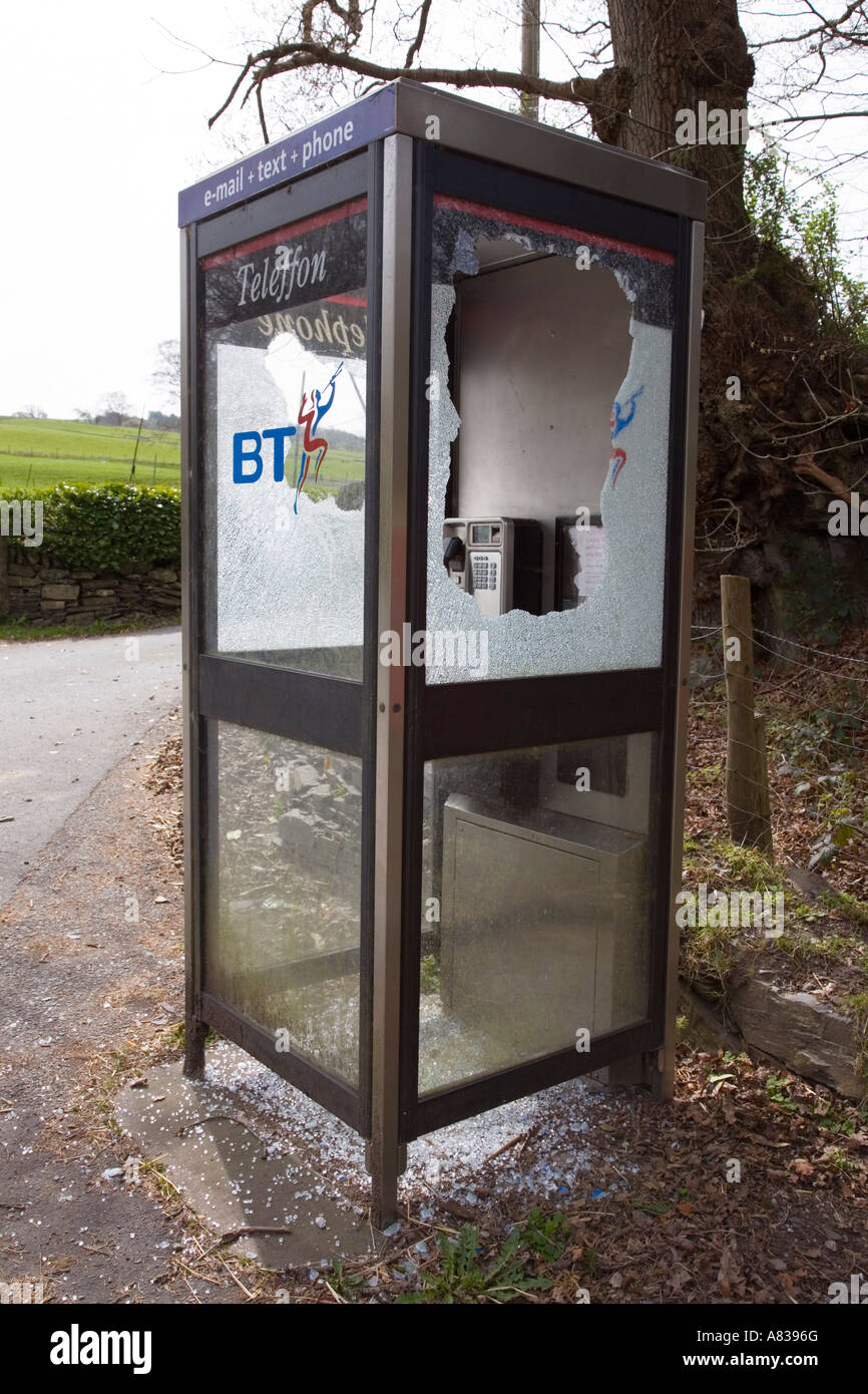 Vandalised modern rural telephone box with hole through broken glass ...
