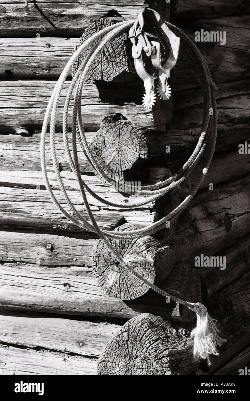 Western spurs and a rope on the corner of a rustic log cabin in Oregon ...