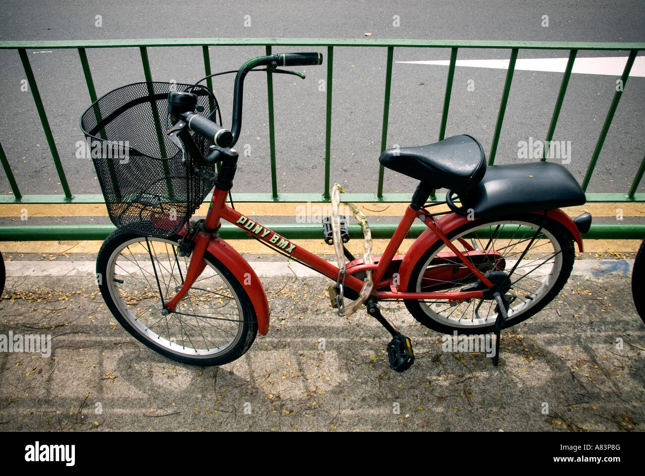 Red bicycle chained up to a green railing on the footpath Stock Photo ...