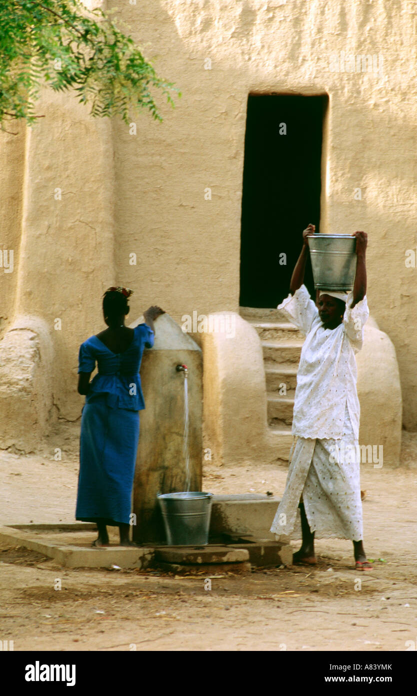 Two women collect water from communal tap Stock Photo - Alamy