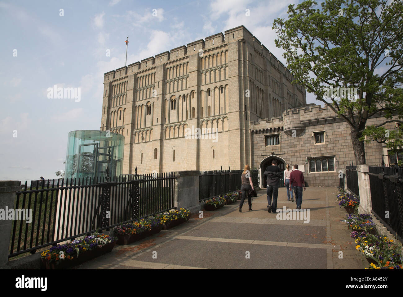 People walking to Norwich castle past the modern glass lift structure ...