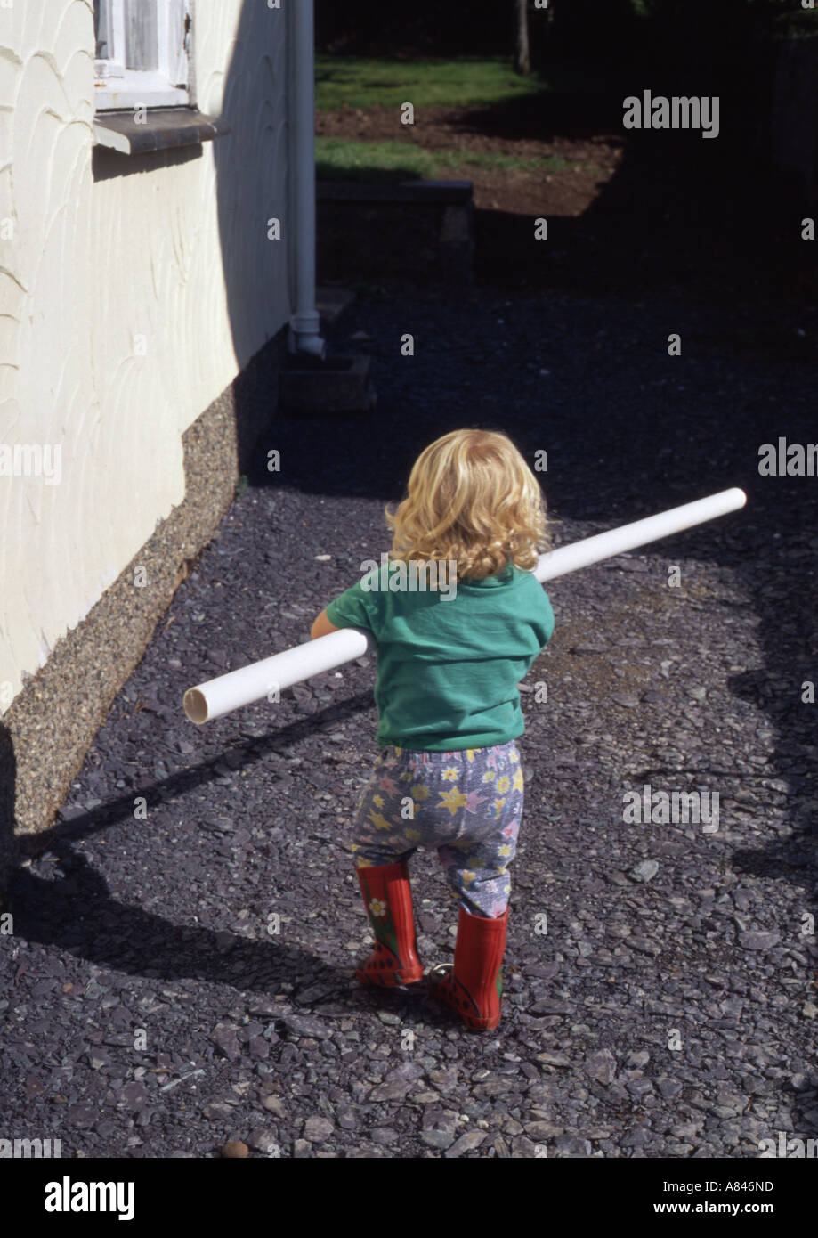 little girl carrying pole in garden Stock Photo - Alamy