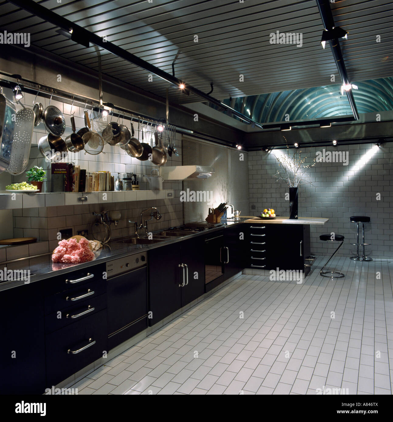 White tiled floor in modern city kitchen with black units and ceiling ...