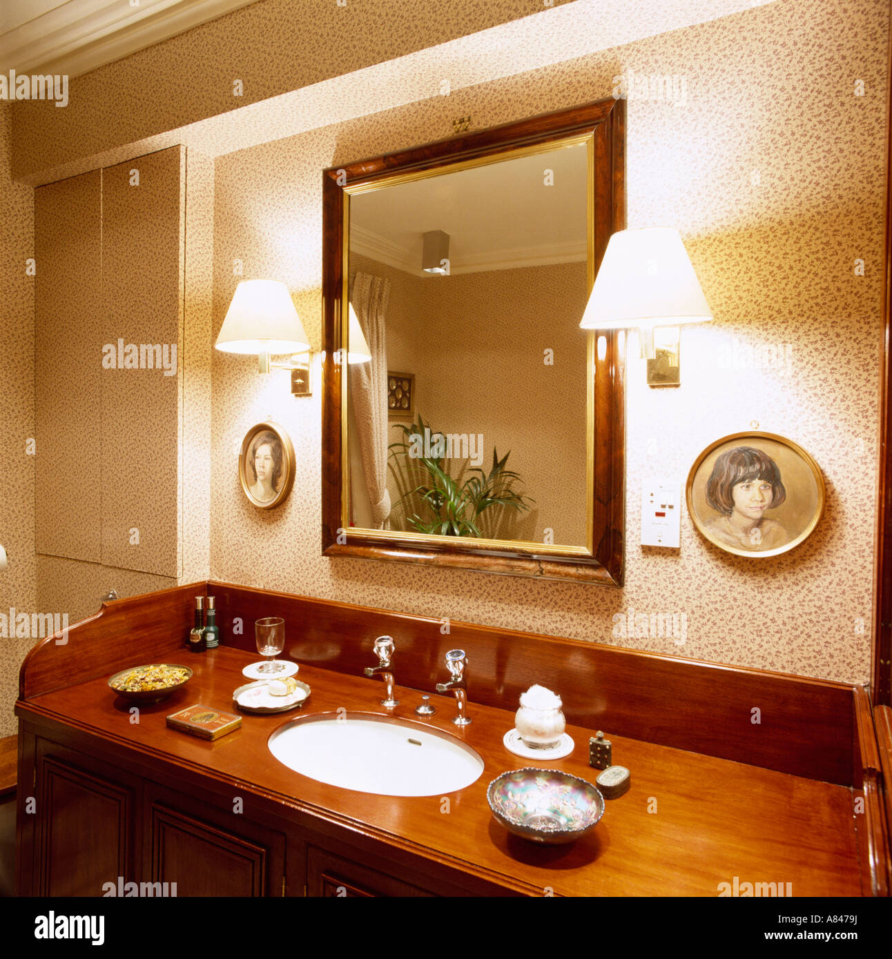 Lighted lamps on either side of framed mirror above basin built into ...