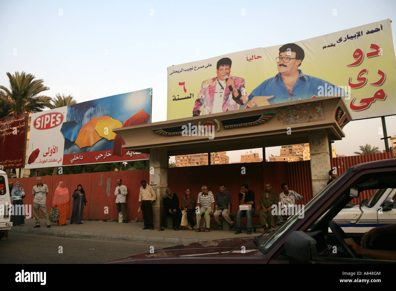 Commuters waiting at bus stop under advertising boards, Cairo, Egypt ...